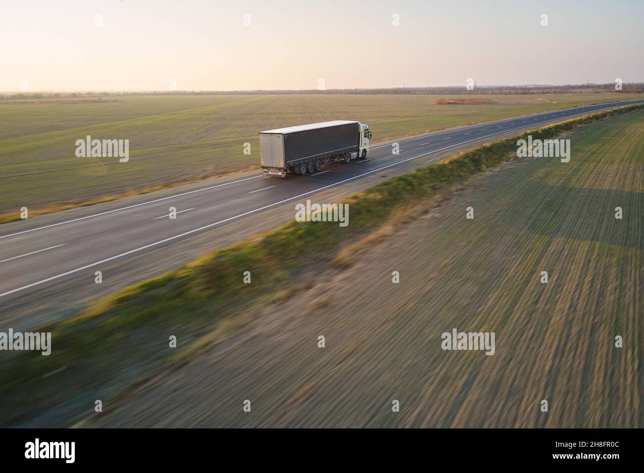 Aerial view of semi-truck with cargo trailer driving on highway hauling ...