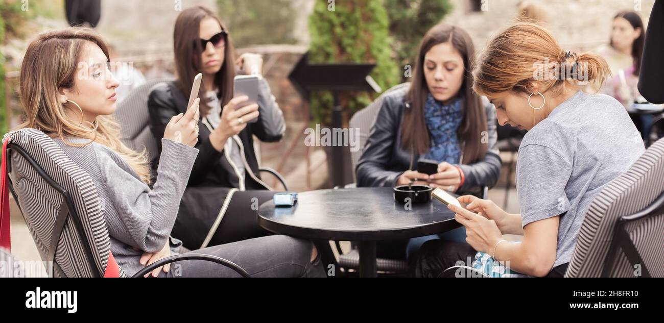 Four woman in cafe using app smartphone playing social network ...