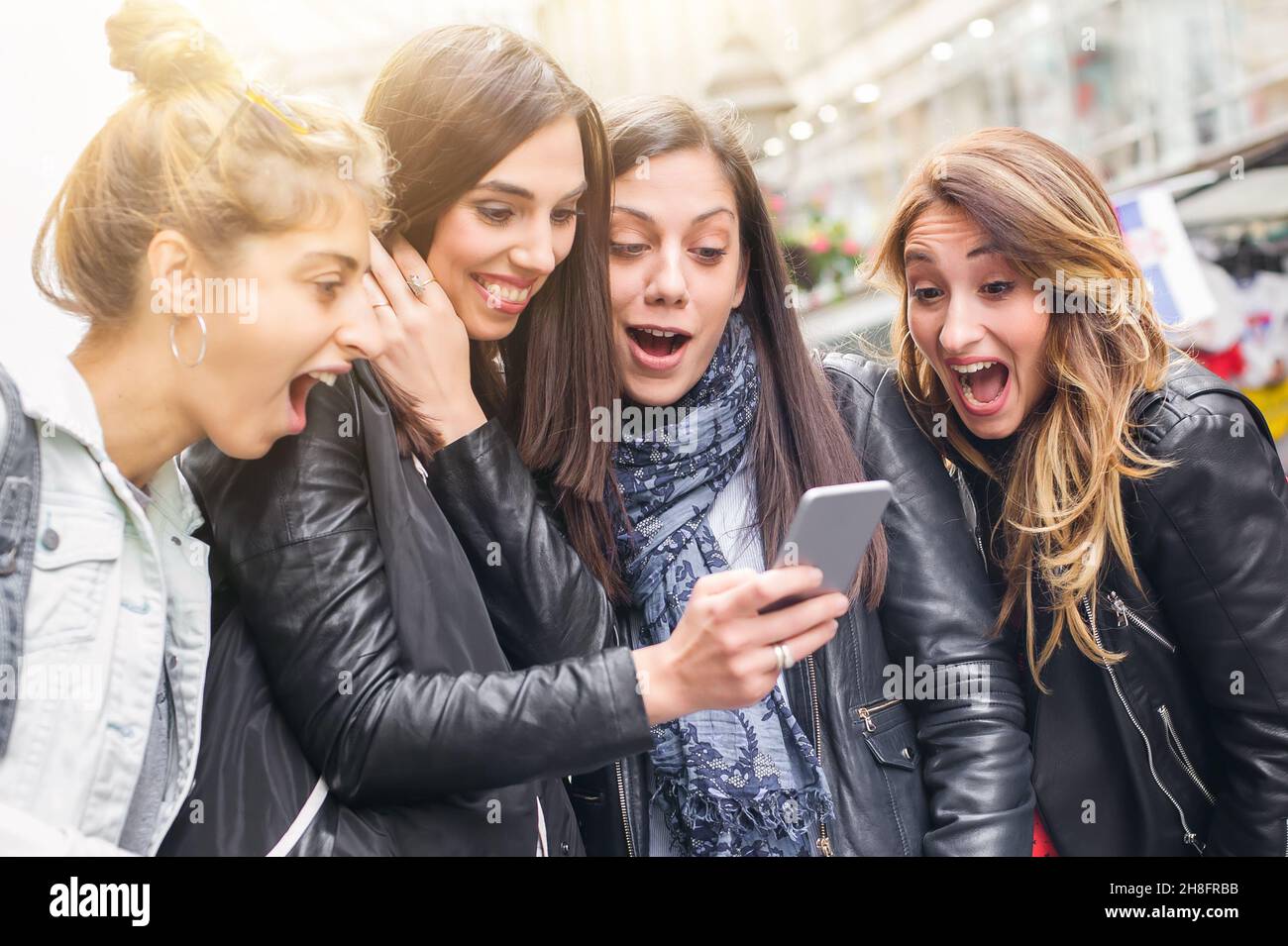 Happy four friends walking on the street and using cellphones. Internet ...