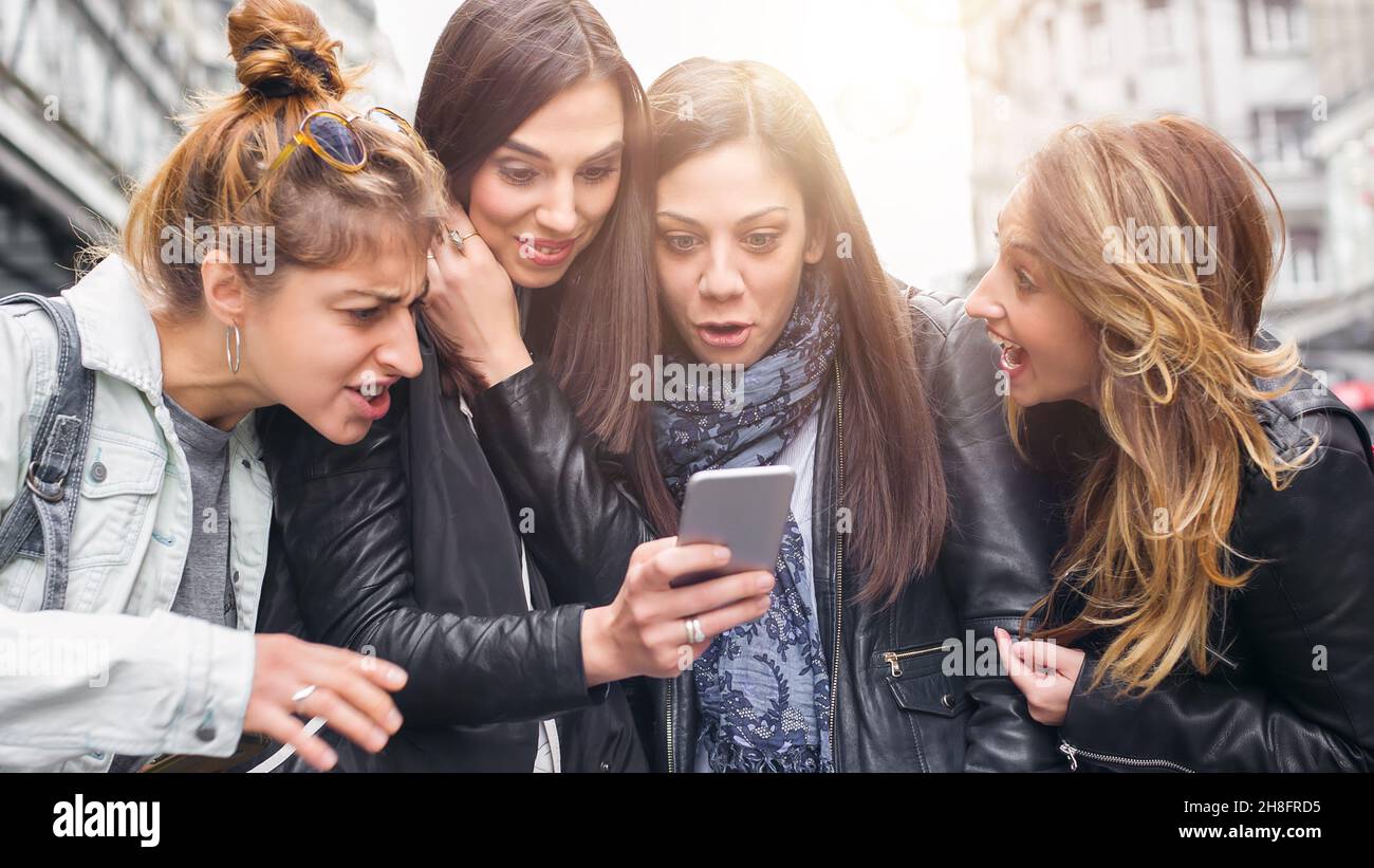 Happy four friends walking on the street and using cellphones. Internet ...