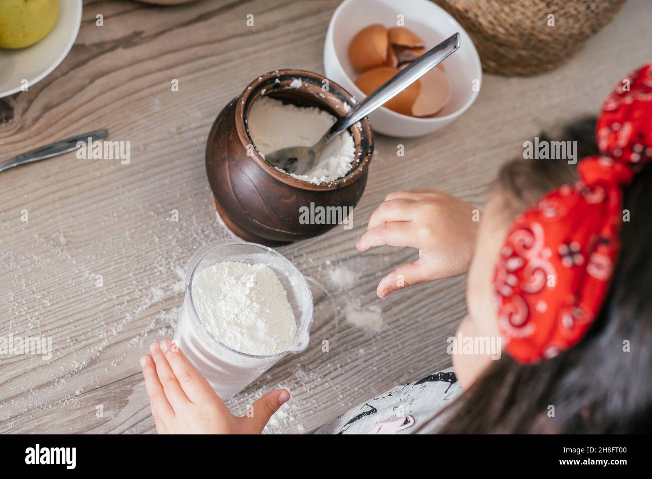Hands of little girl in red headband bake apple pie in kitchen. Child ...