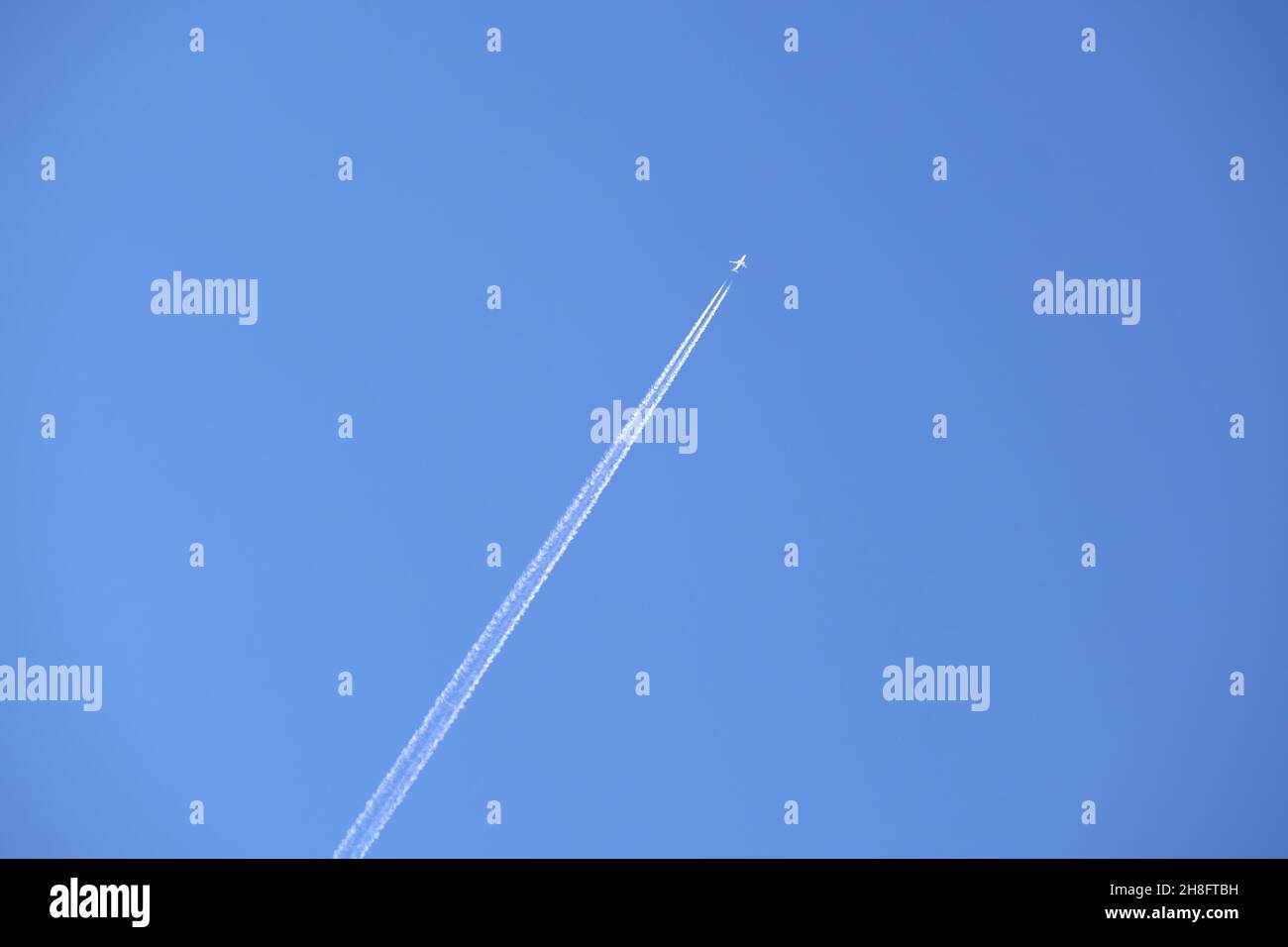 Distant passenger jet plane flying on high altitude on clear blue sky ...