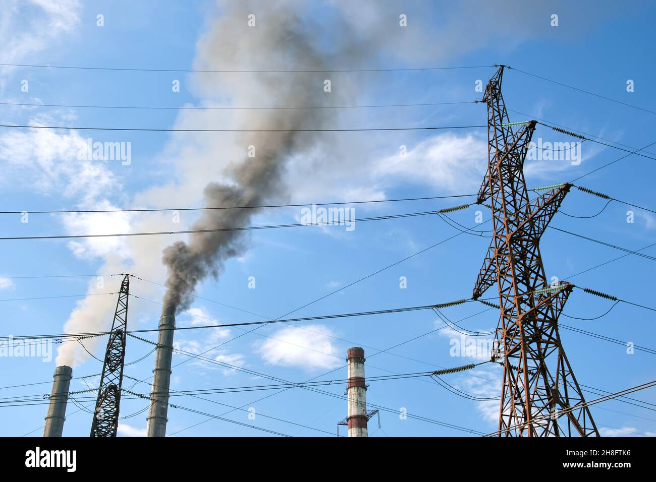 High voltage electric pylons against coal power plant high pipes with ...