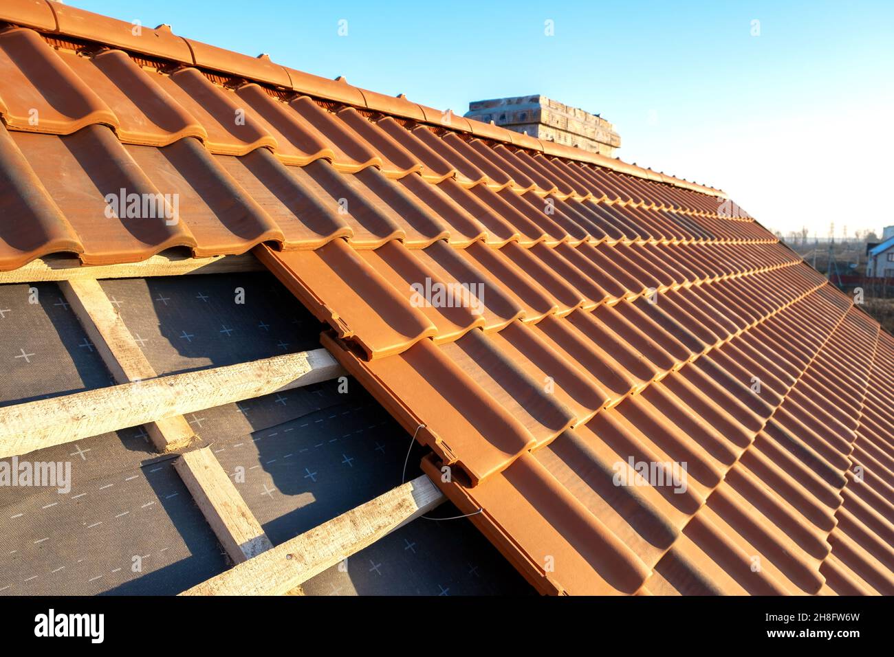 Overlapping rows of yellow ceramic roofing tiles mounted on wooden ...