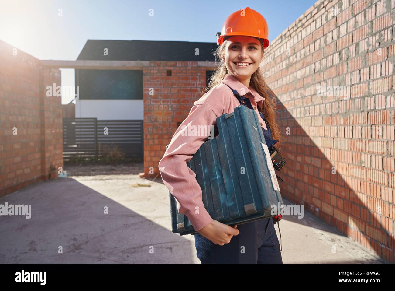 Radiant female builder standing with a big box of instruments Stock ...