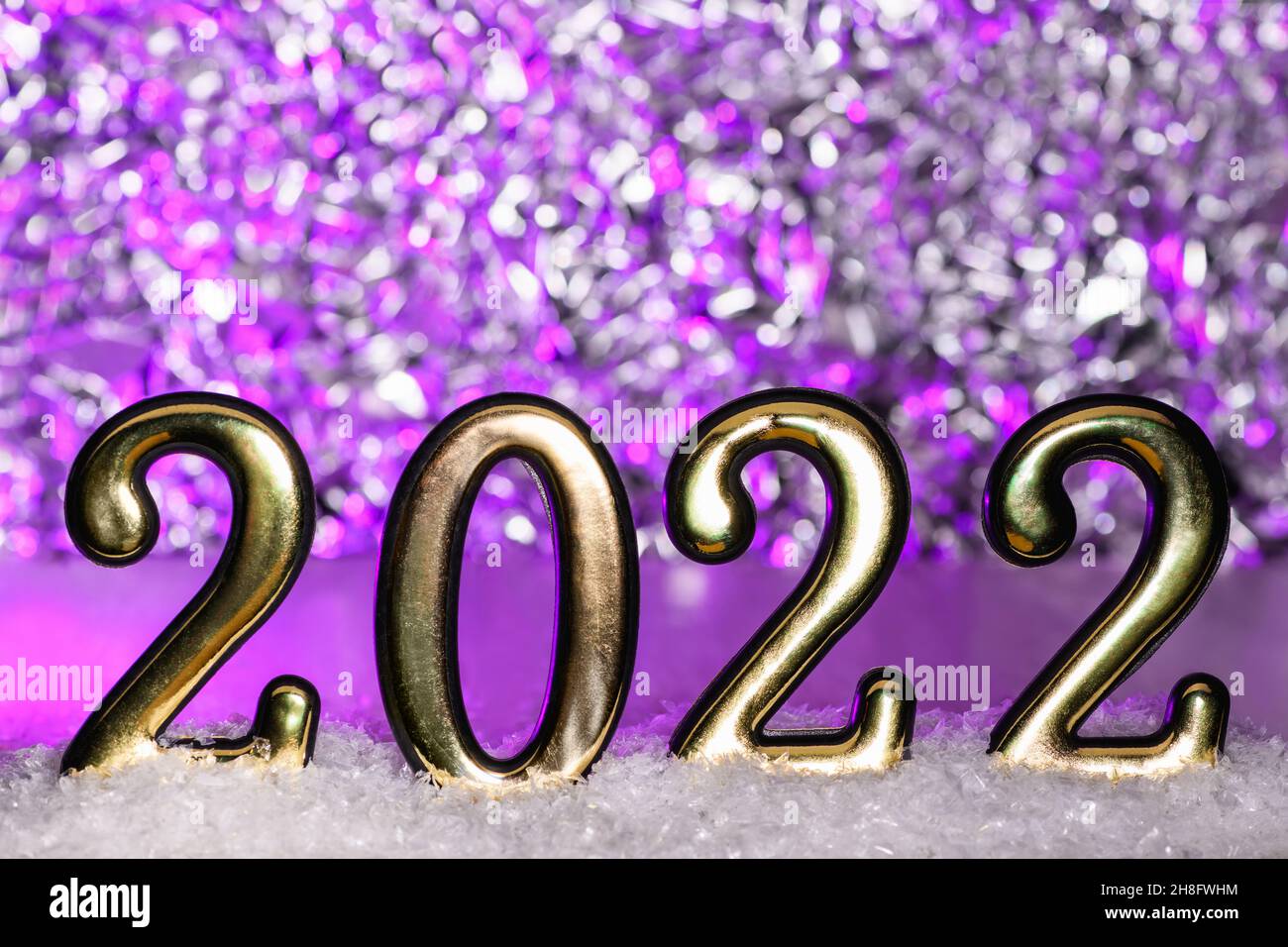 Gold numbers 2022 on snow with purple backlight. New year backdrop with ...