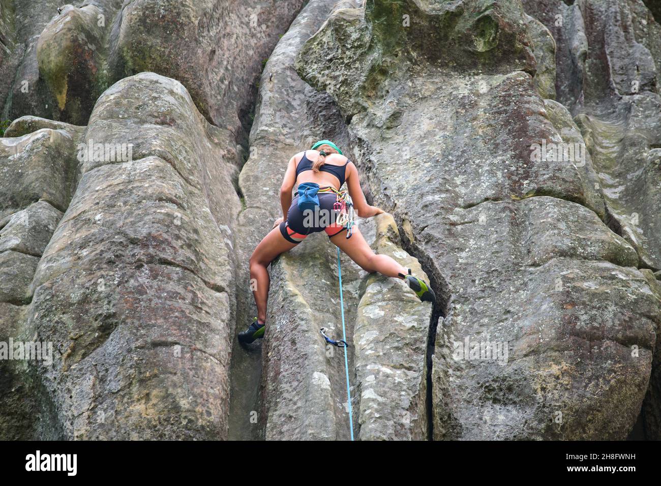 Strong female climber climbing steep wall of rocky mountain ...