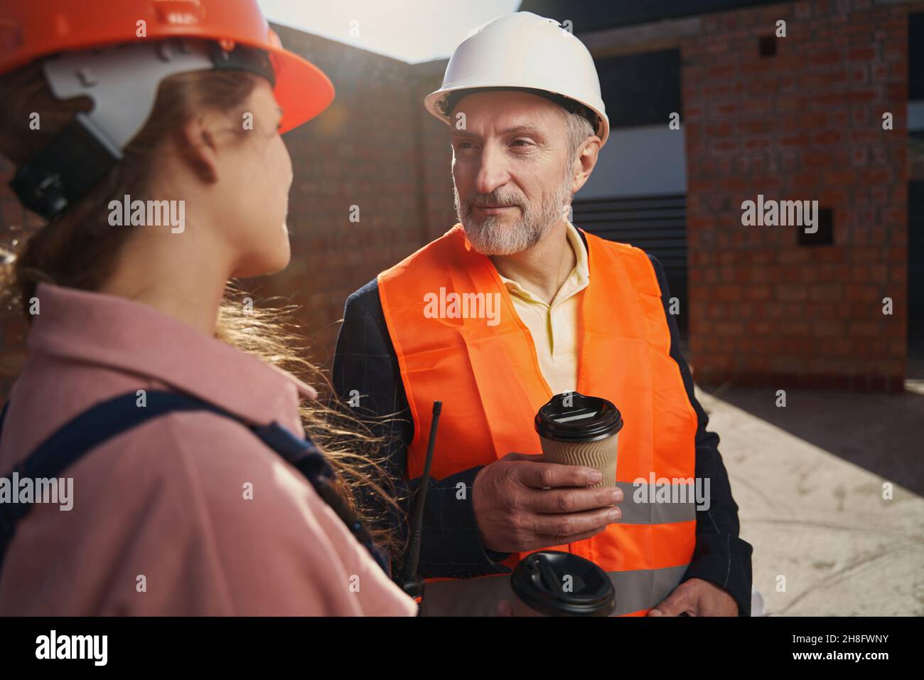 Professional construction workers having a conversation over coffee ...