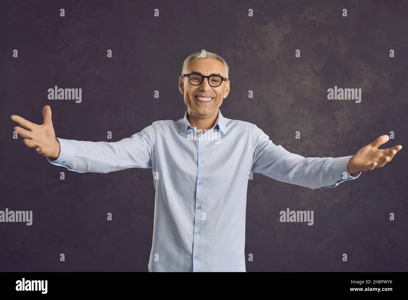 Happy senior man smiling and spreading his arms wide open to welcome ...