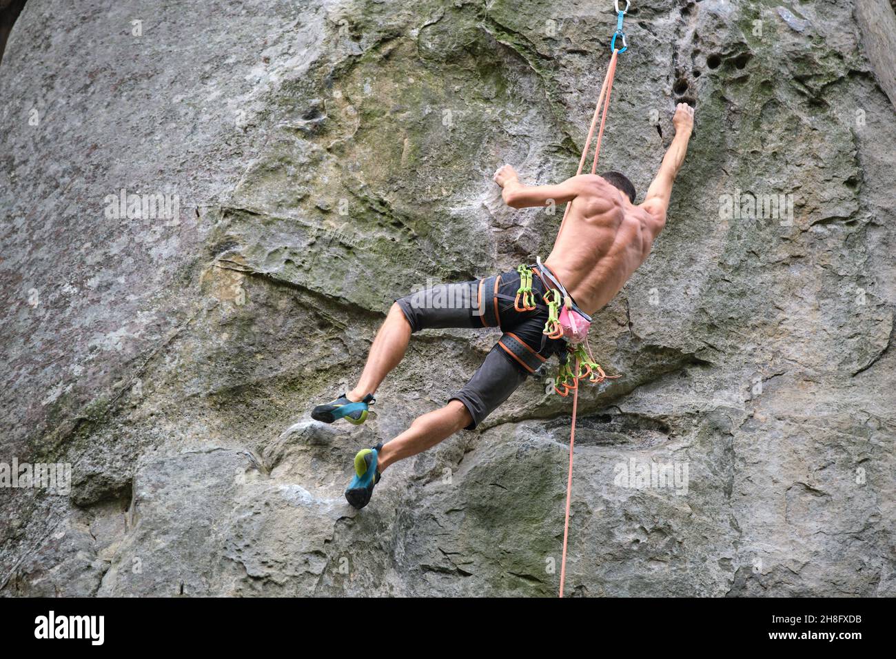 Young man climbing steep wall of rocky mountain. Male climber overcomes ...