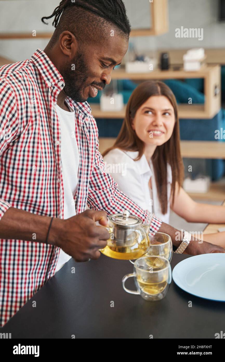Smiling happy guy making chamomile tea for two Stock Photo - Alamy