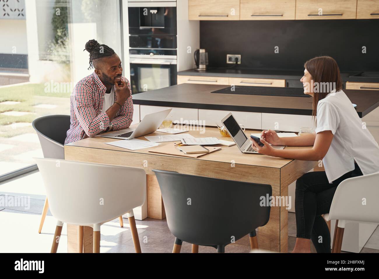 Two telecommuters at desk smiling at each other Stock Photo - Alamy