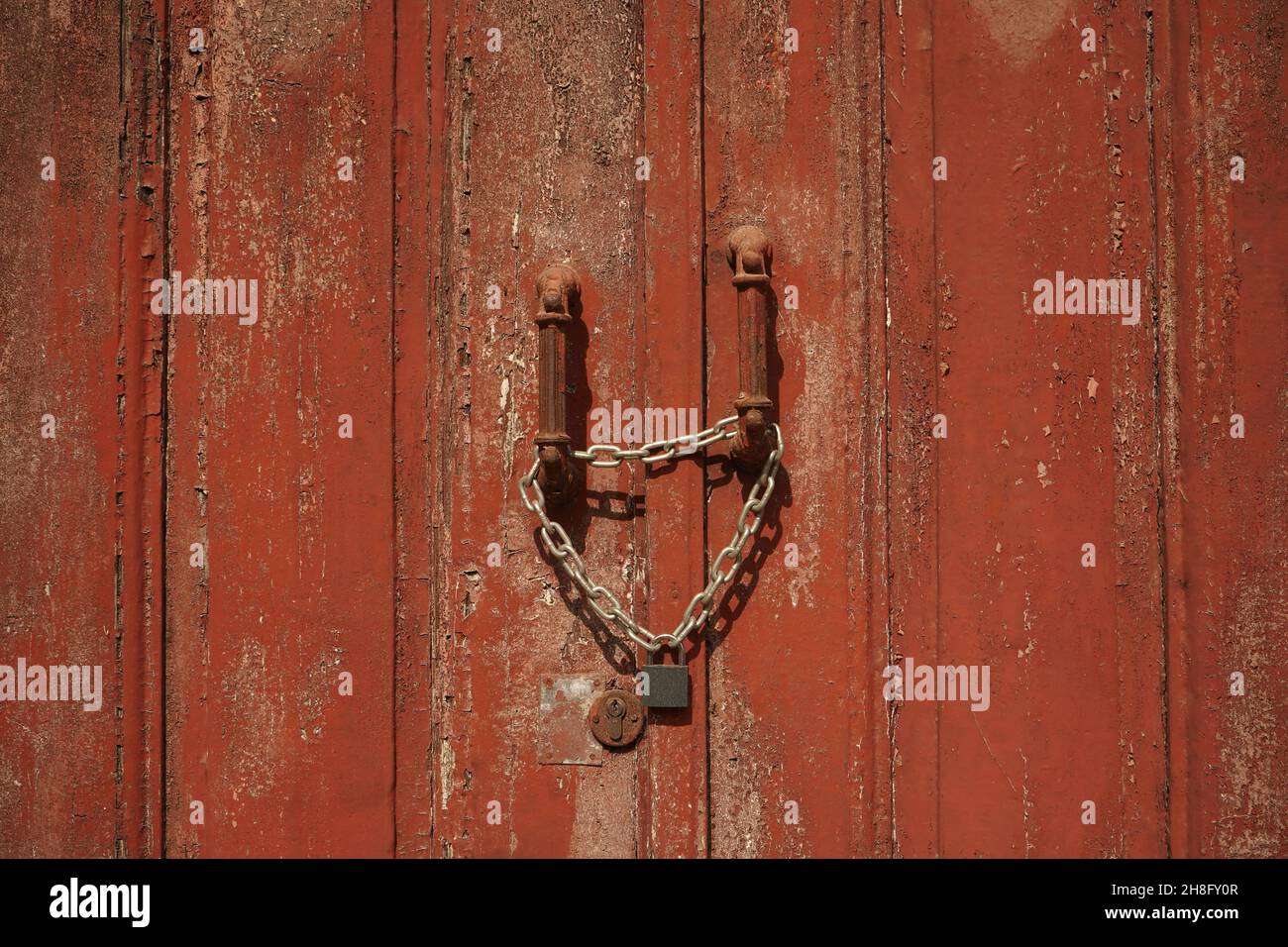 A burgundy double wooden door chained closed Stock Photo - Alamy