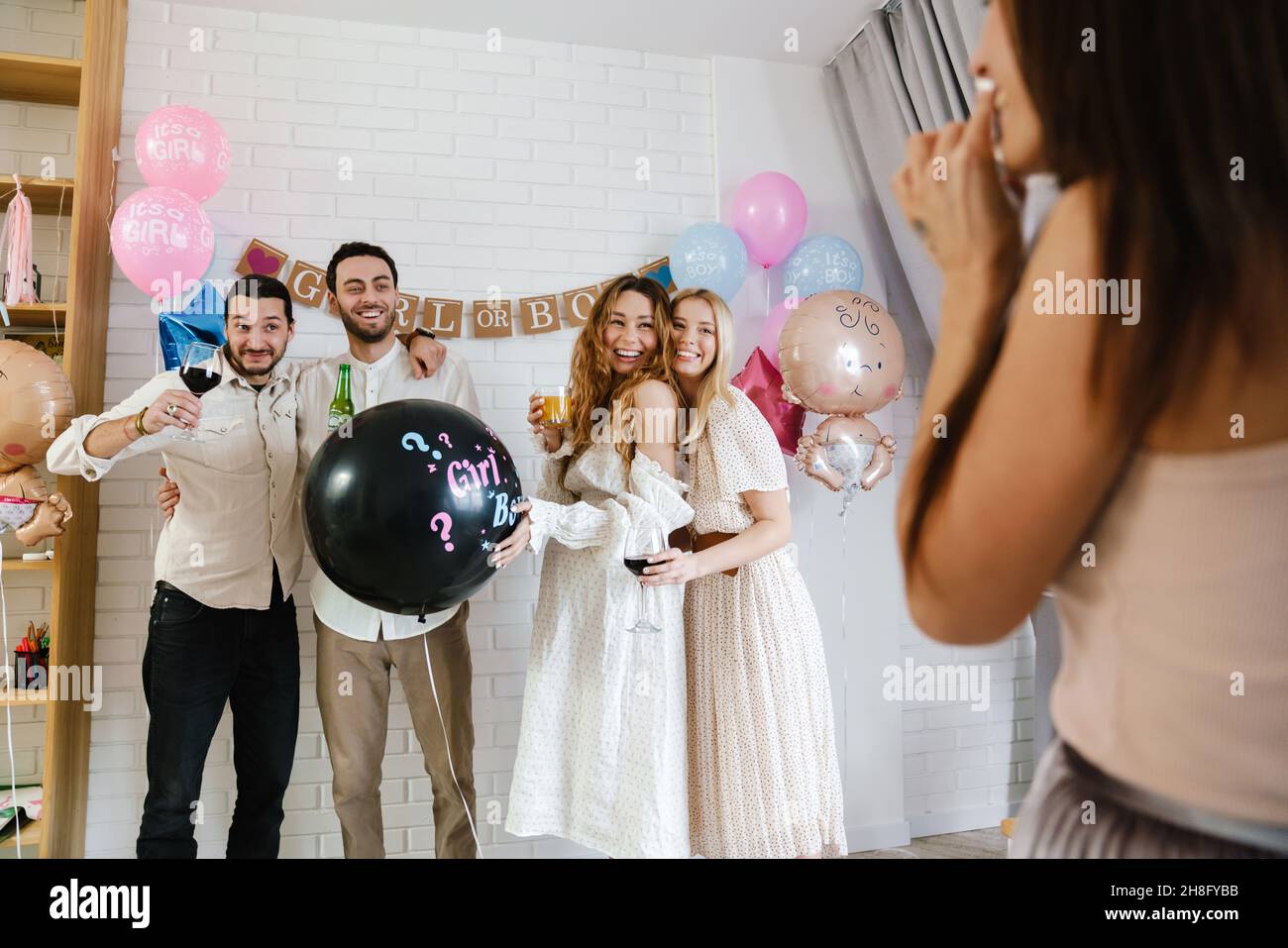 Group of happy friends at a gender reveal baby shower, holding balloon ...