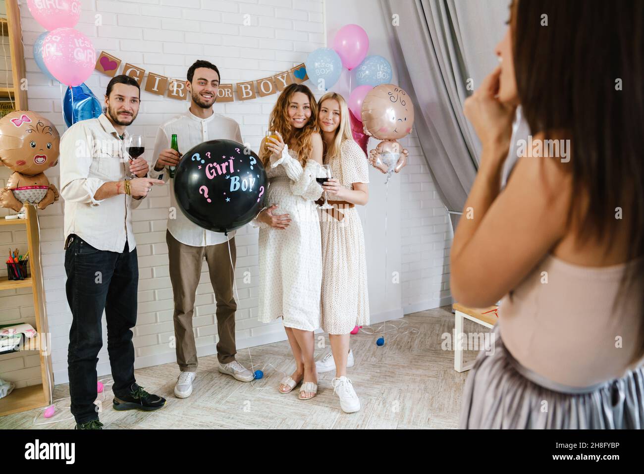 Group of happy friends at a gender reveal baby shower, holding balloon ...