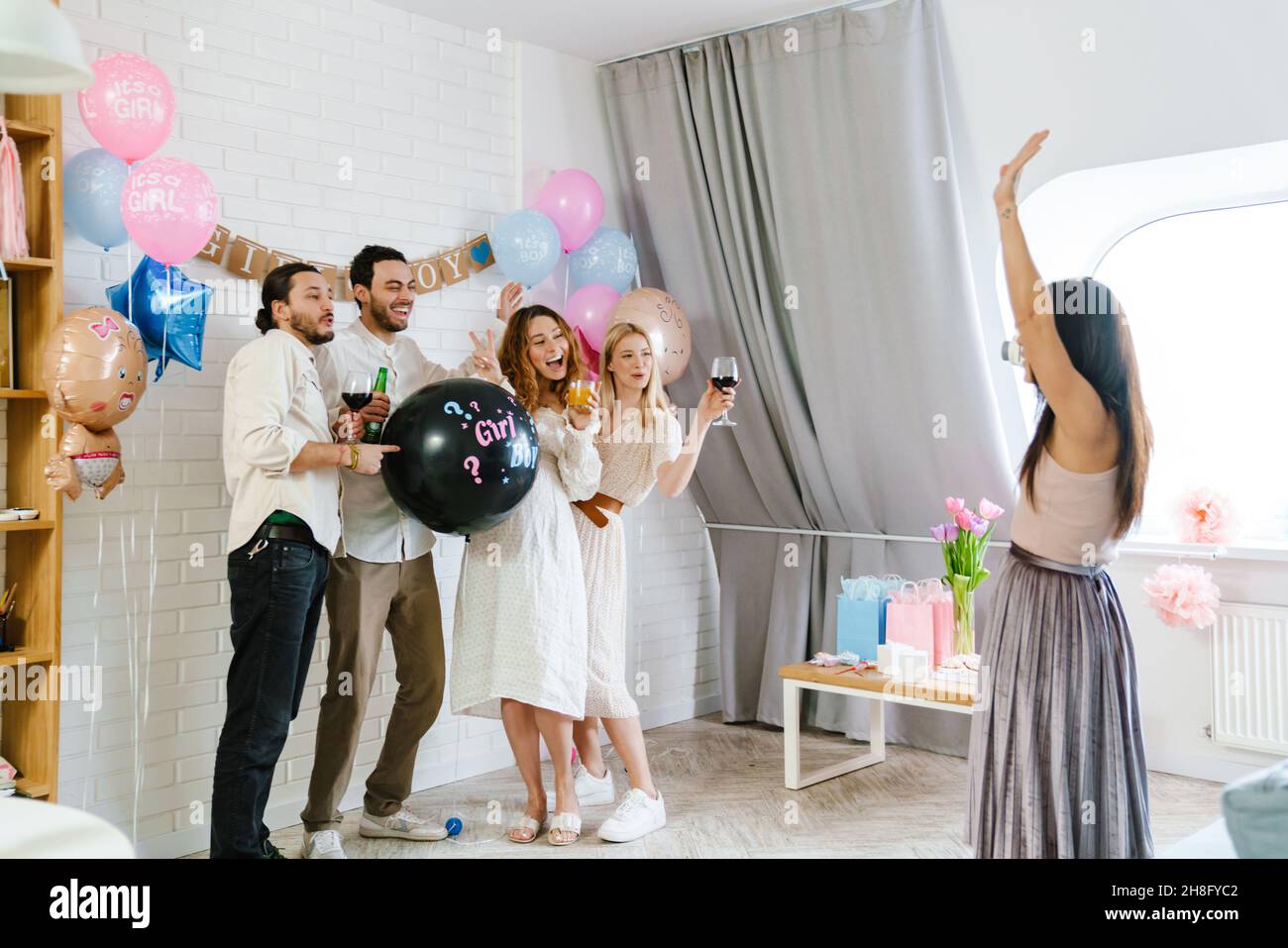 Group of happy friends at a gender reveal baby shower, holding balloon ...
