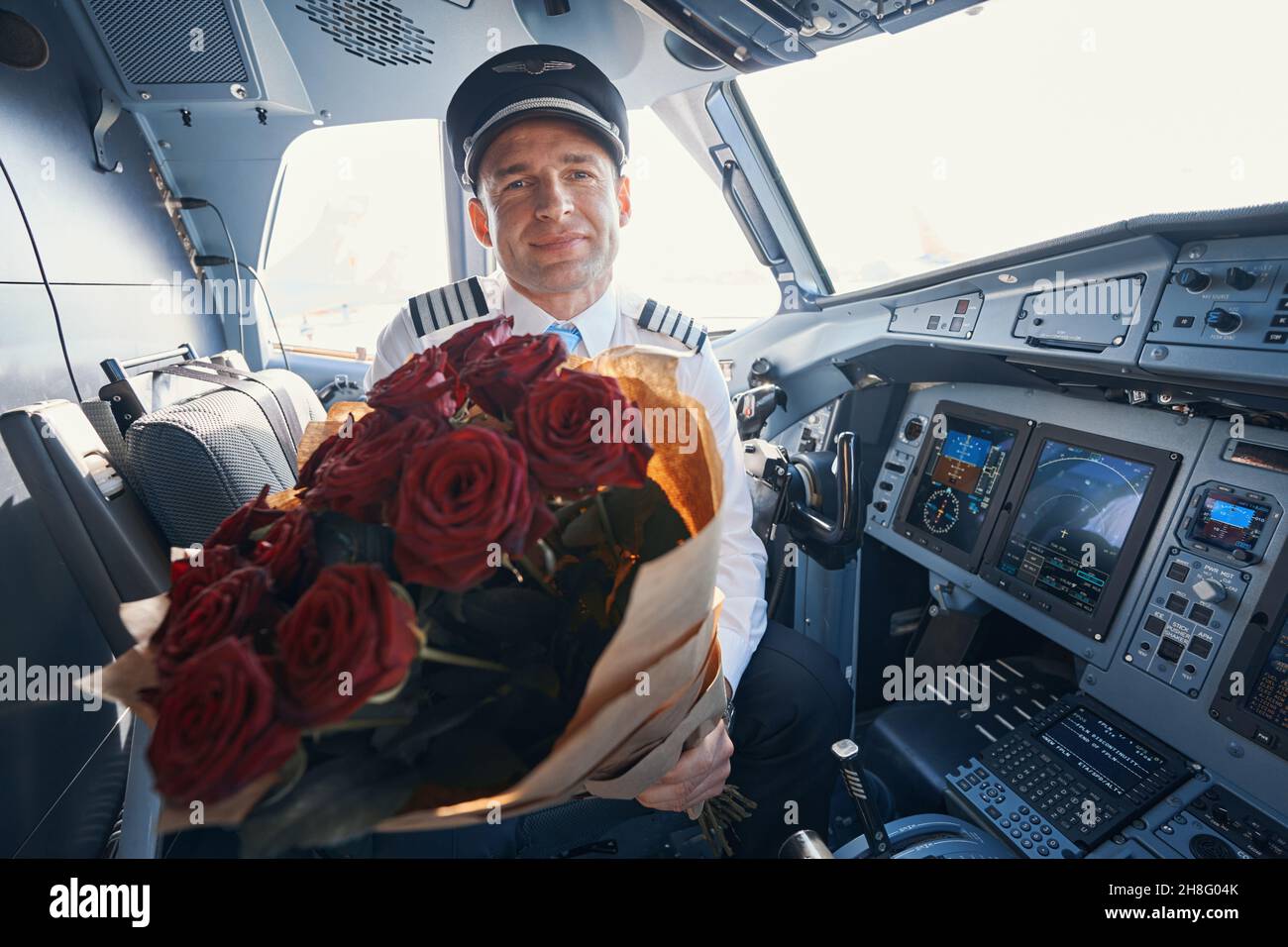 Pilot in cockpit holding out bouquet of flowers Stock Photo - Alamy