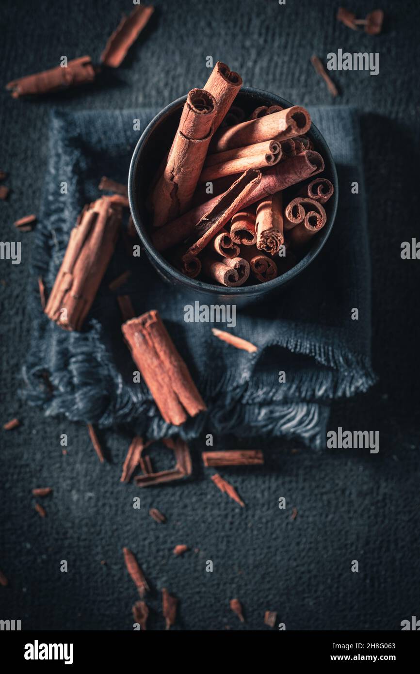 Cinnamon sticks in a cup on a dark background. The basic spice in the ...