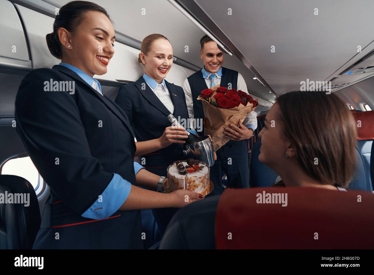 Airplane cabin crew presenting flowers and cake to passenger Stock ...
