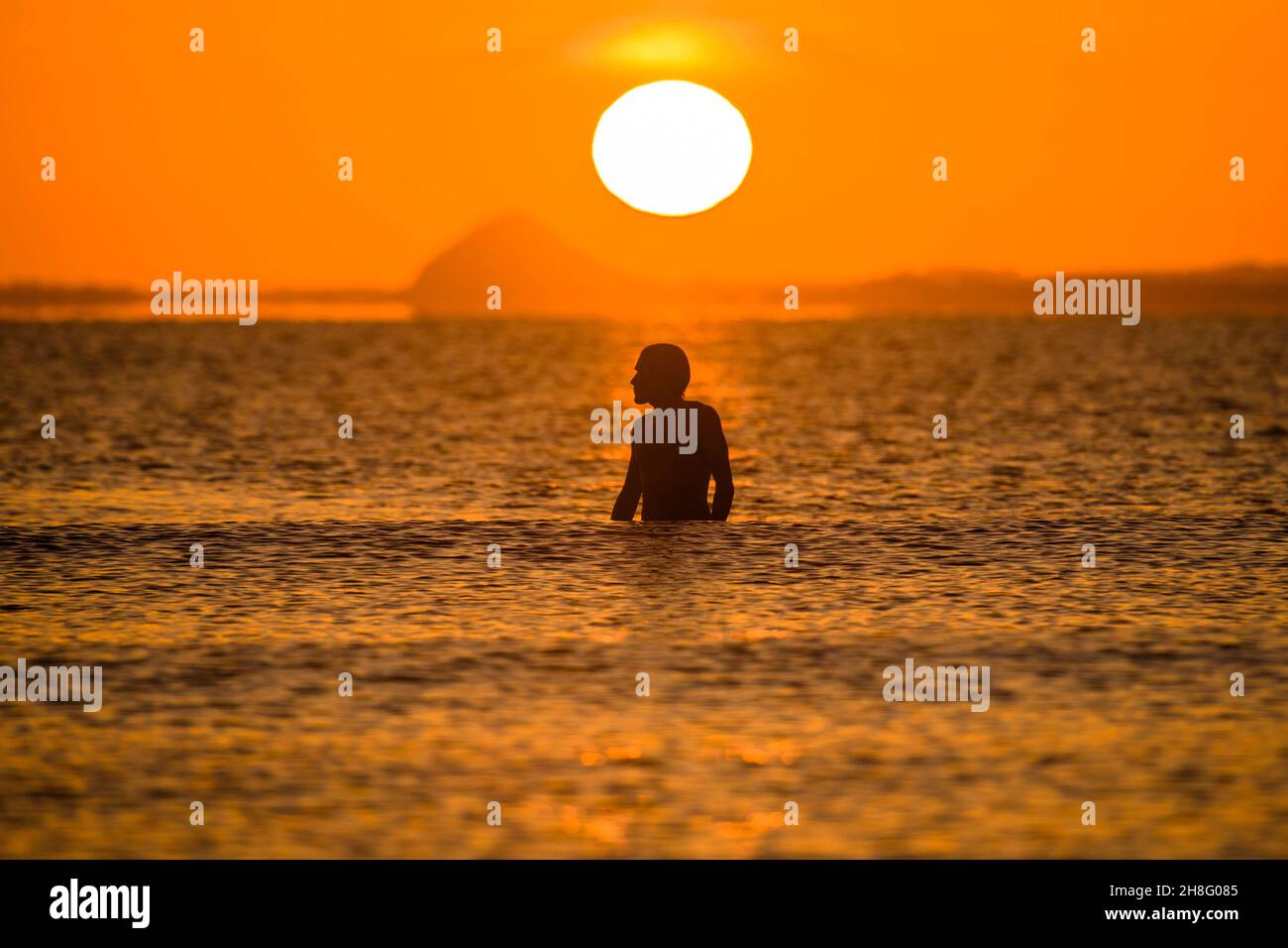 A wild swimmer walks into the cold waters as the sunrises behind North ...