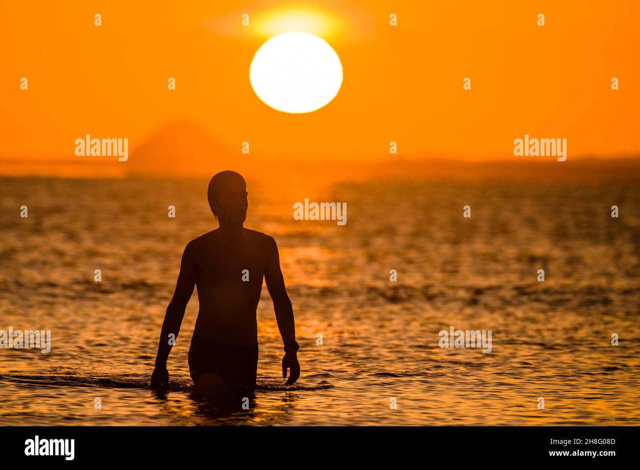 A wild swimmer walks into the cold waters as the sunrises behind North ...