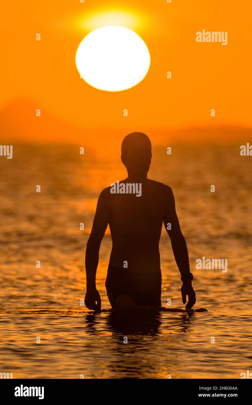 A wild swimmer walks into the cold waters as the sunrises behind North ...