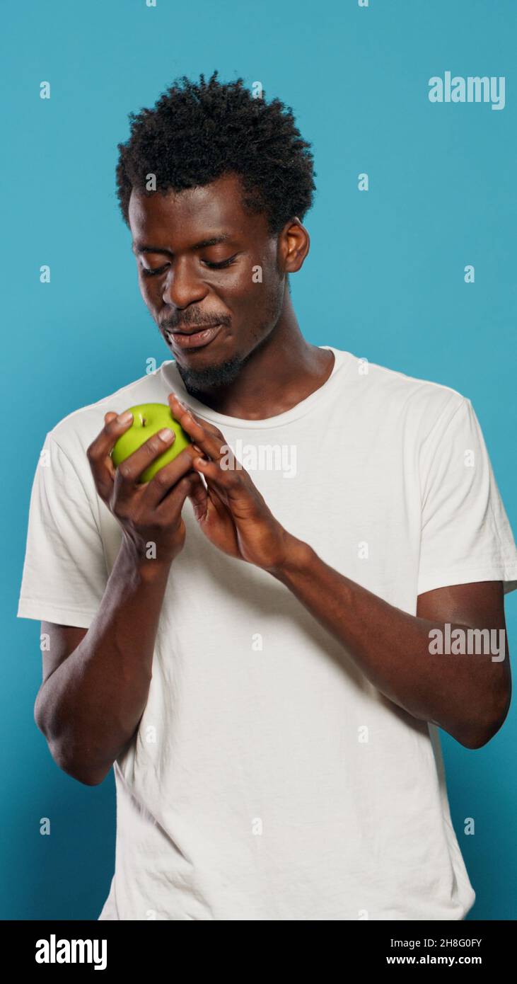 Vegetarian man playing with green apple in studio. Joyful person ...