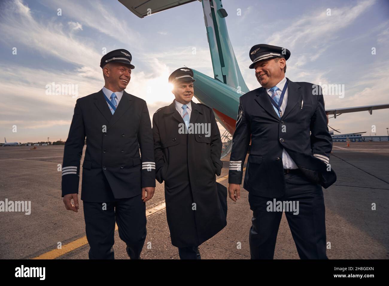 Three pilot friends moving through runway and laughing Stock Photo - Alamy