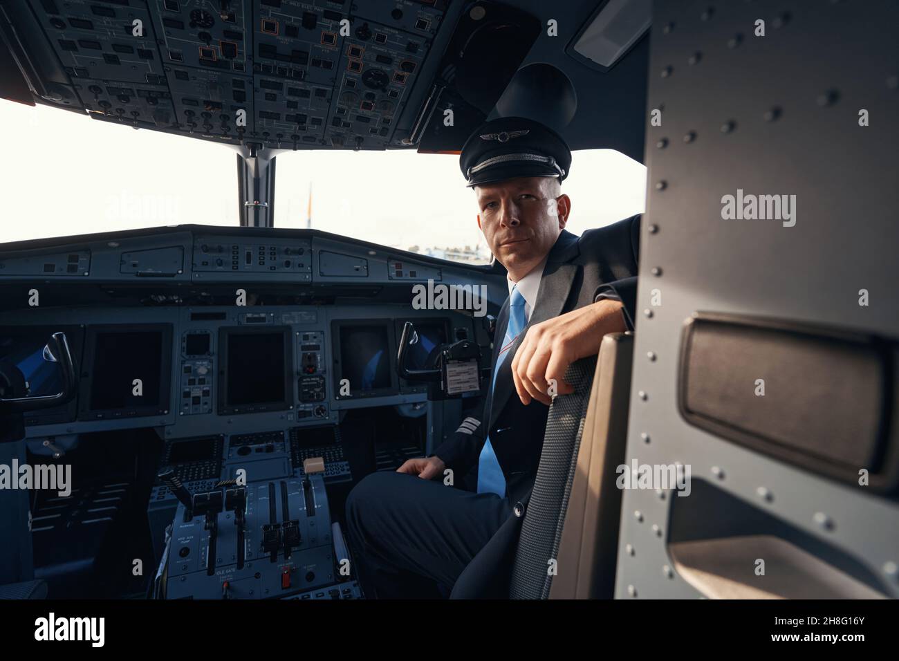 Calm pilot in cockpit turning to entrance from his seat Stock Photo - Alamy