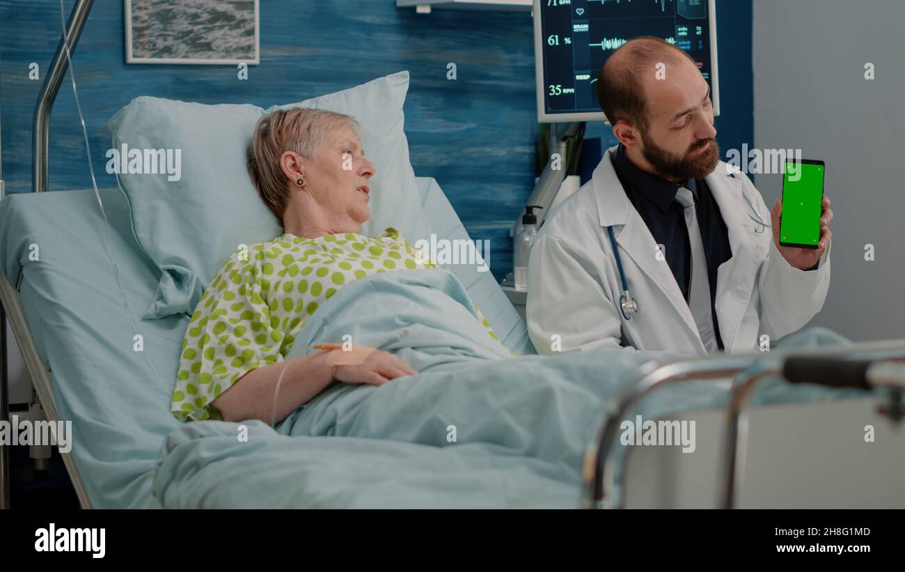 Doctor and sick patient looking at green screen on phone at nursing ...