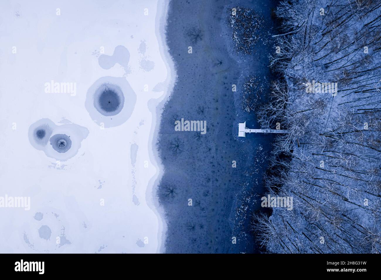 Pier, frozen lake and ice holes for fishing in winter, Poland. Aerial ...