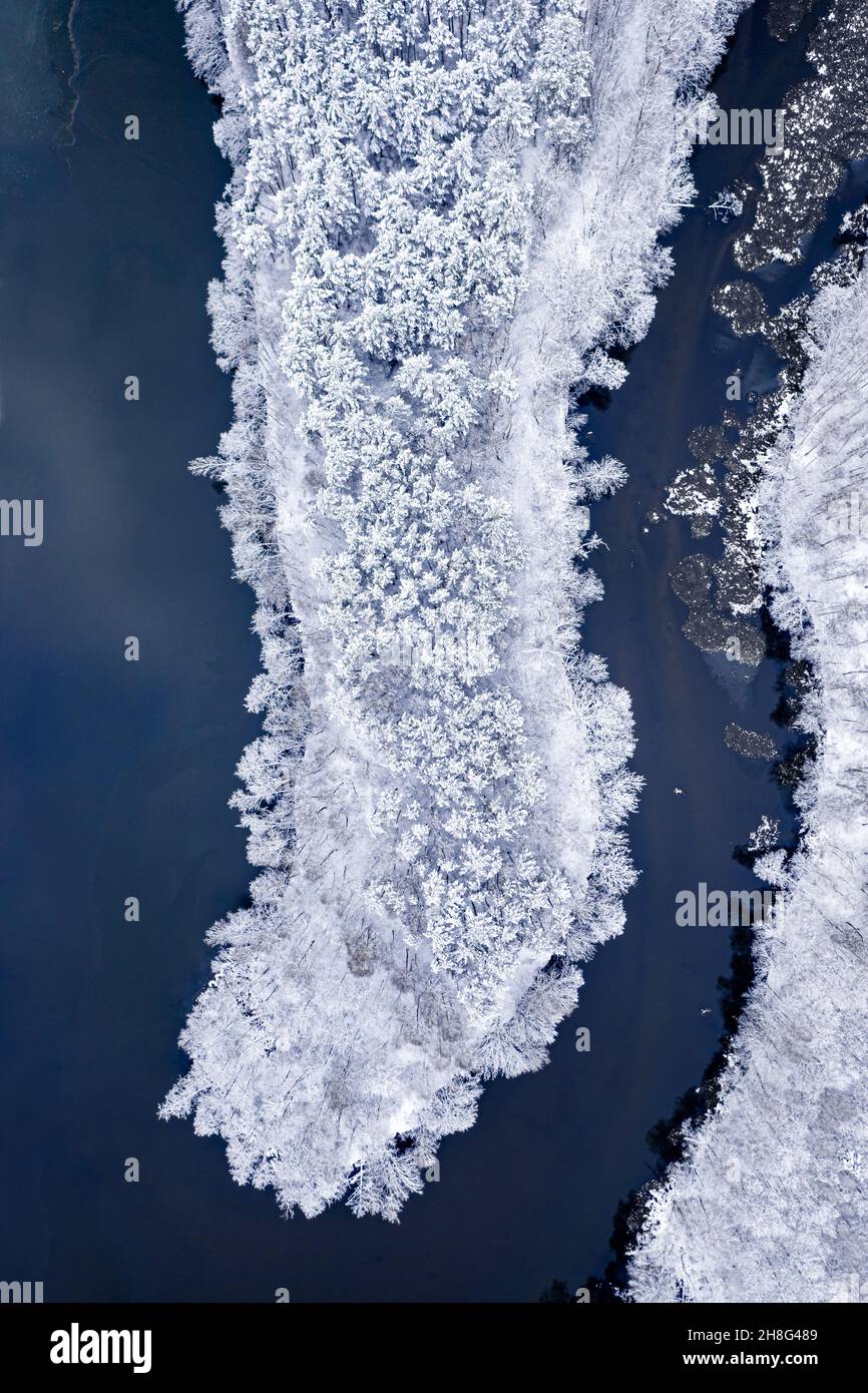 Top down view of river and frozen snowy forest in winter in Poland ...