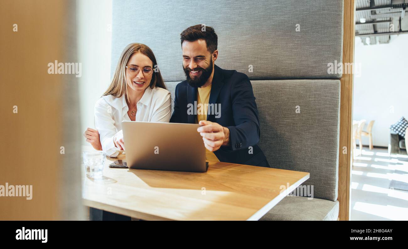 Two business professionals smiling at a laptop screen cheerfully. Happy ...