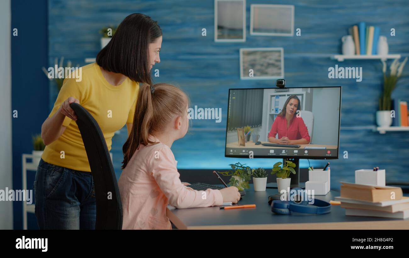 Schoolgirl using video call for online lesson with teacher and mother ...