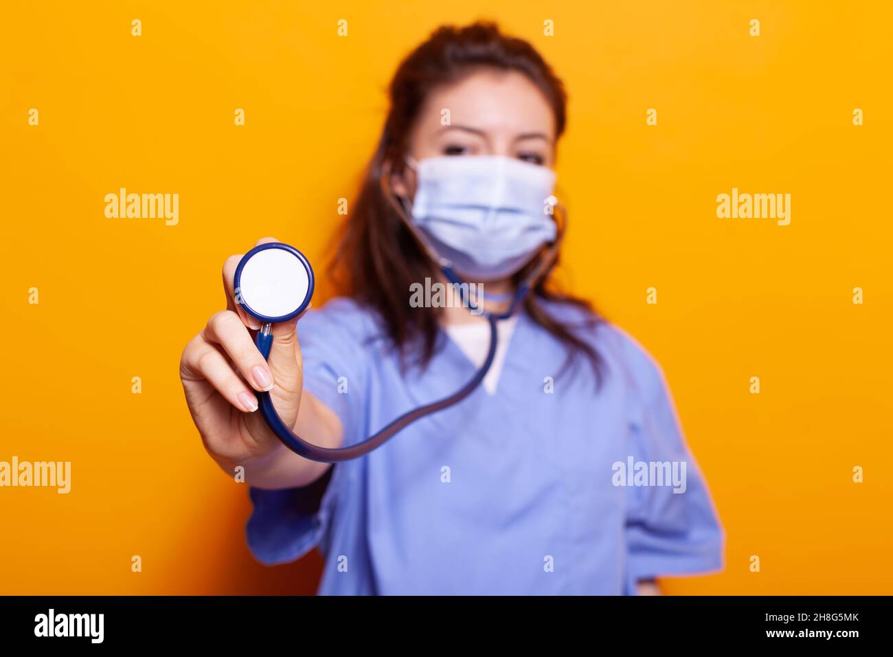 Close up of nurse with face mask showing stethoscope on camera in ...