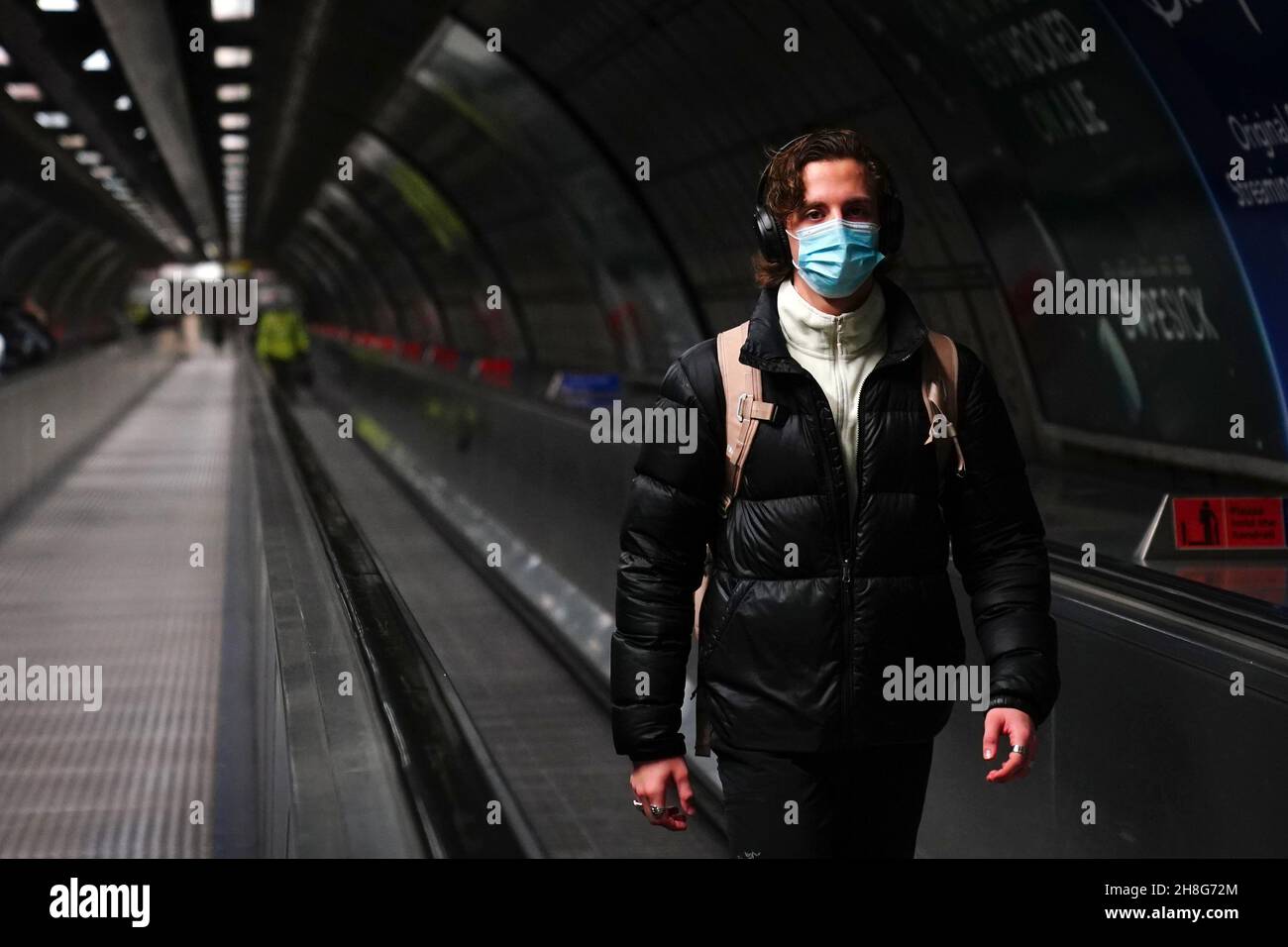 A commuter in a London underground tube station wears a face covering ...