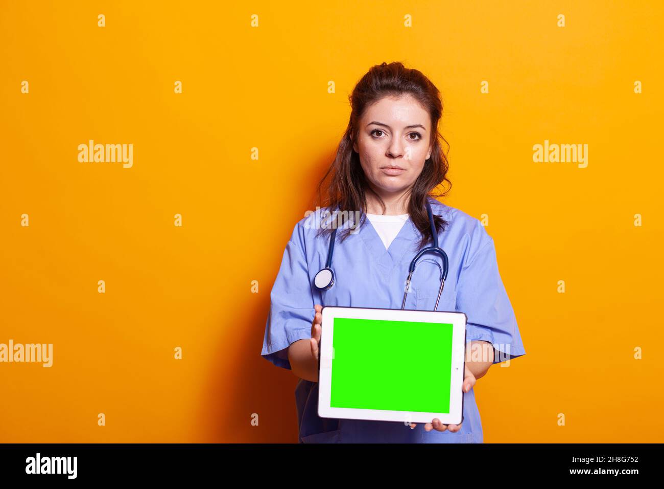 Medical assistant showing digital tablet with horizontal green screen ...