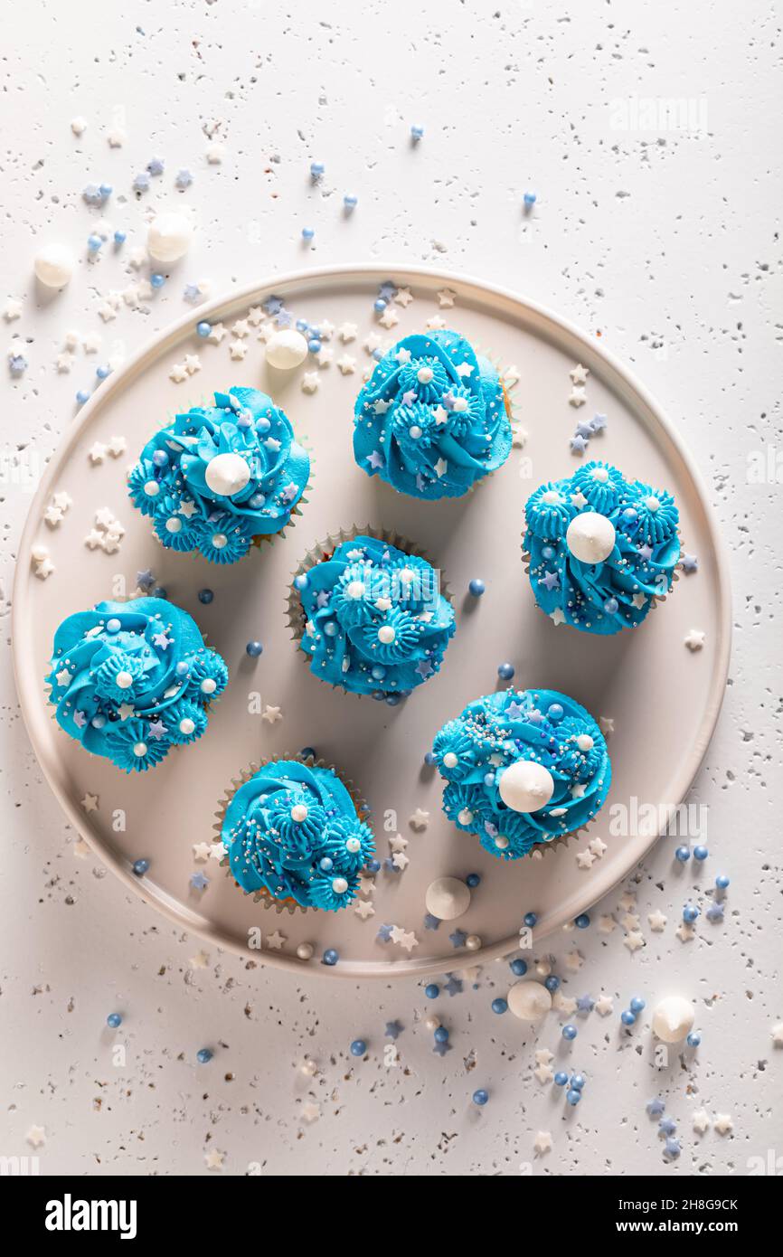 Delicious cupcakes with white sprinkles and blue cream. Perfect blue dessert with sprinkles ...