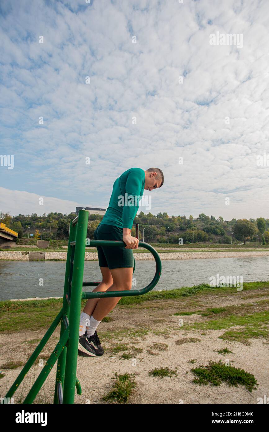 Attractive and handsome strong guy is doing some hard pull ups on the ...