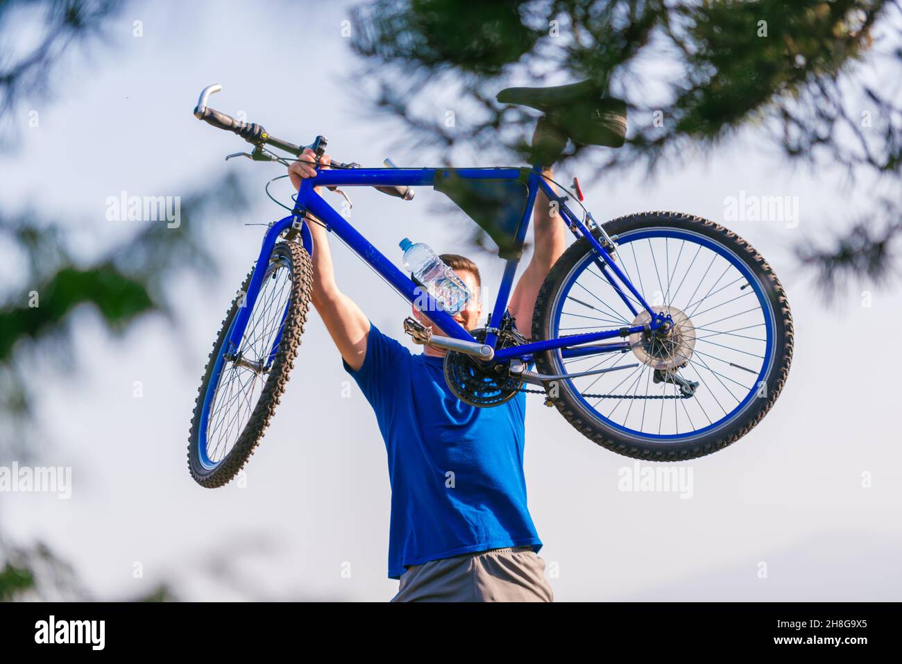 A strong male mountain biker is lifting his bike while smiling Stock ...