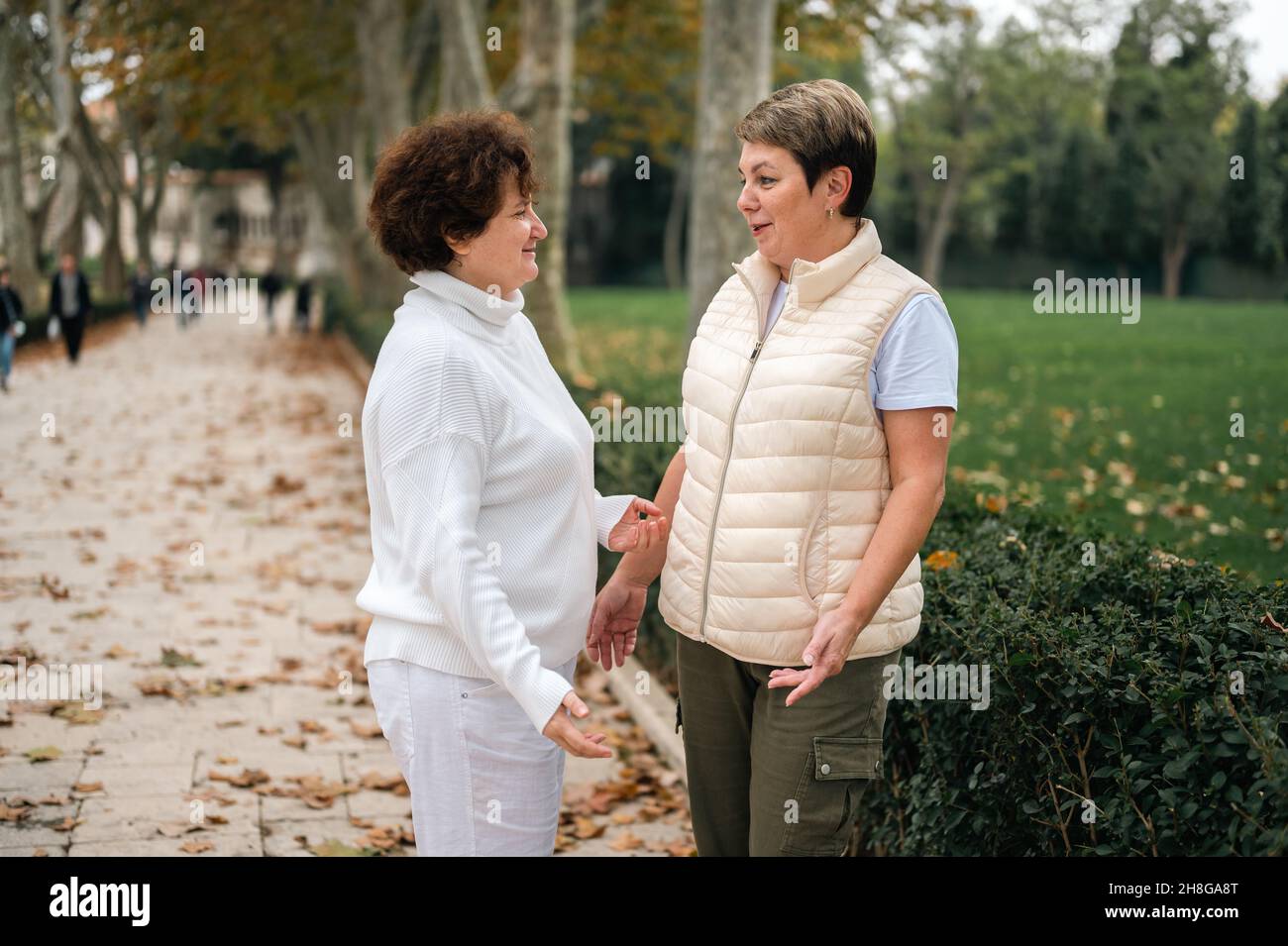 Two Senior Women Smiling to Each Other. two old friends met in the park ...