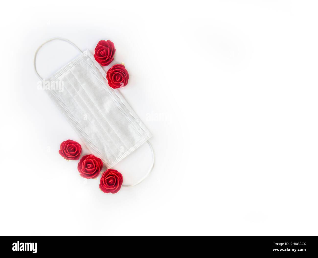 Red roses and a protective medical face mask isolated on white ...