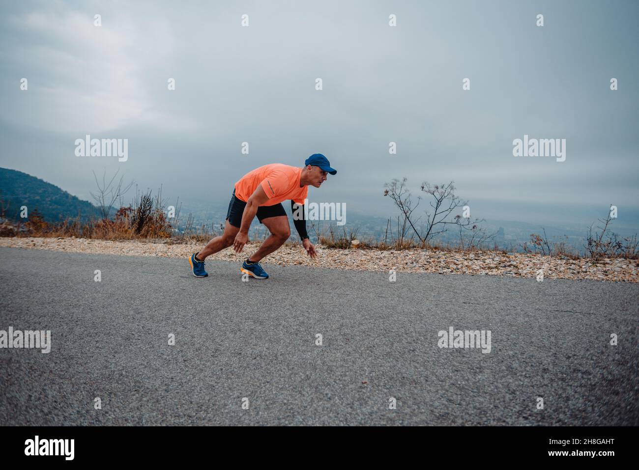 Healthy middle aged man doing a sprint exercise on a concrete road ...