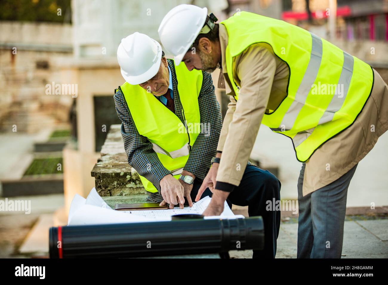 Two construction workers are looking at the plans on the paper while ...