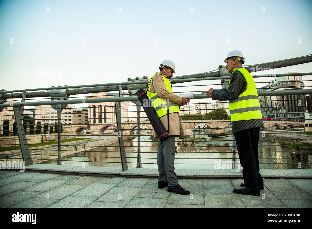 Two senior construction managers arestanding while talking about the ...