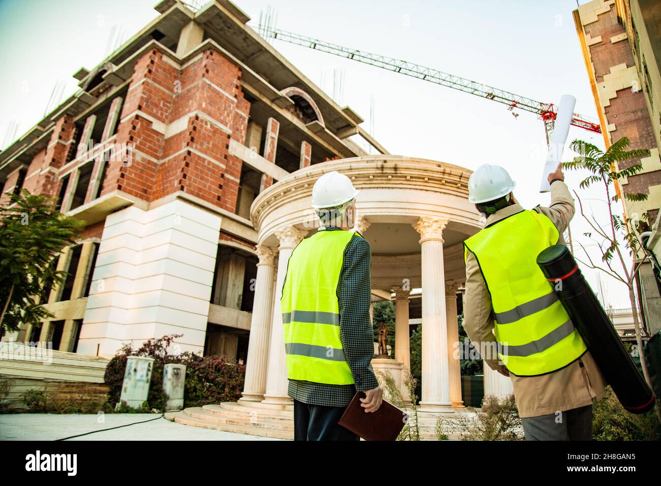 Two construction workers are looking at the construction area while ...