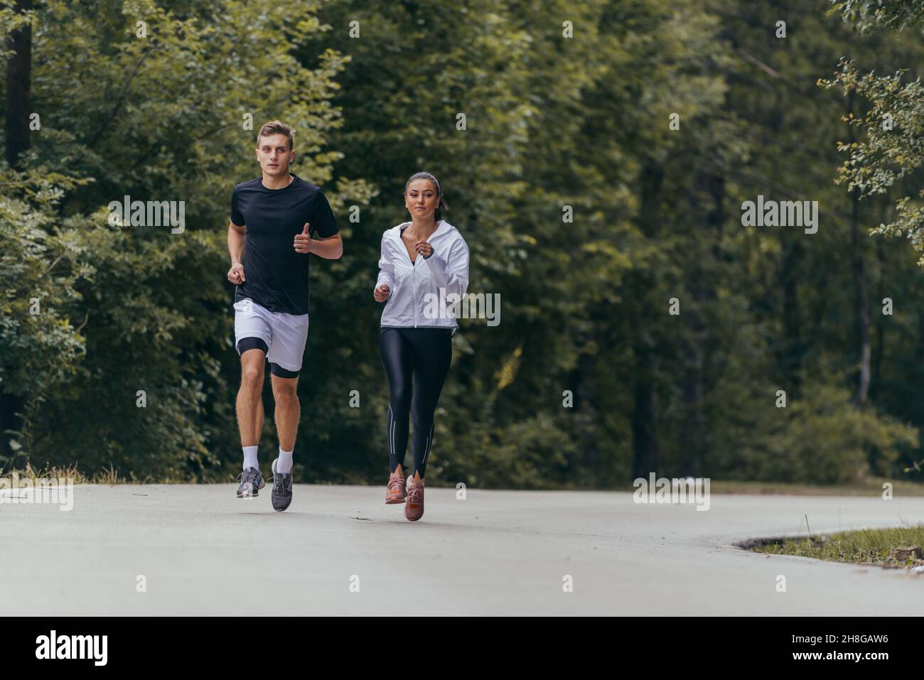 Athletic couple running on a street next to each other. Nature,fit and ...