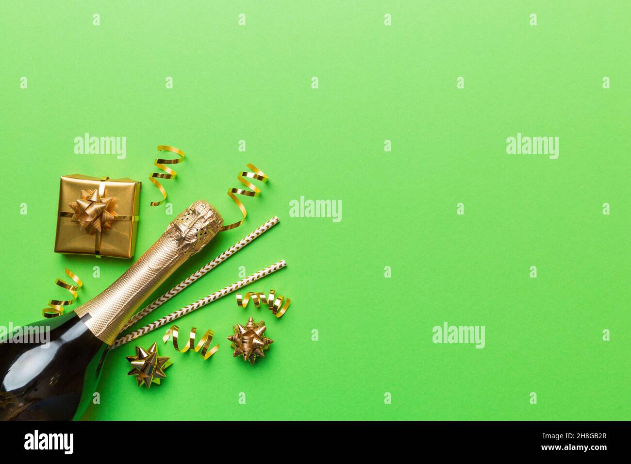 Bottle of champagne with colored glitter, confetti and gift box space ...