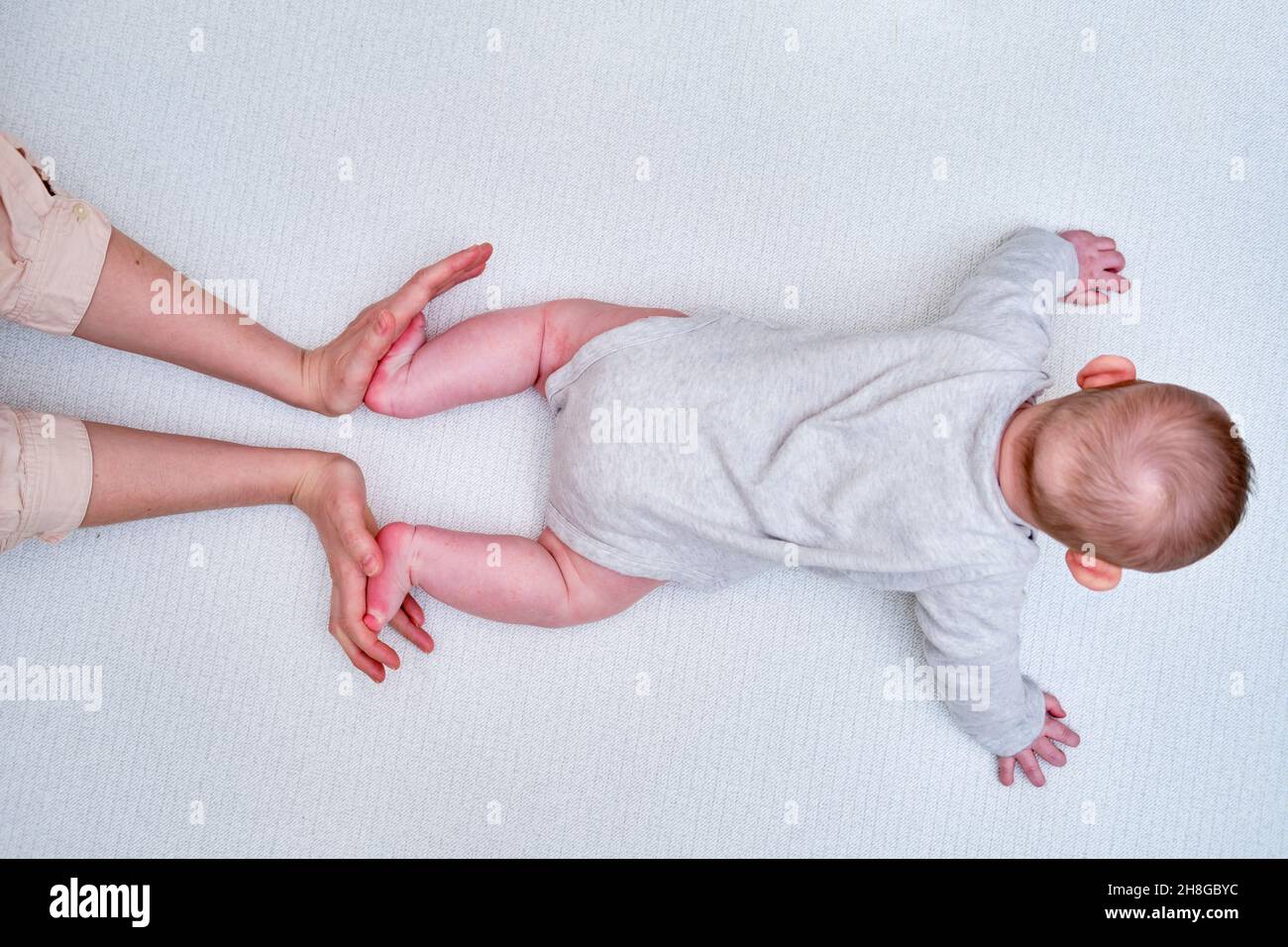 Woman mother helps to crawl infant baby by pushing off from palms of ...