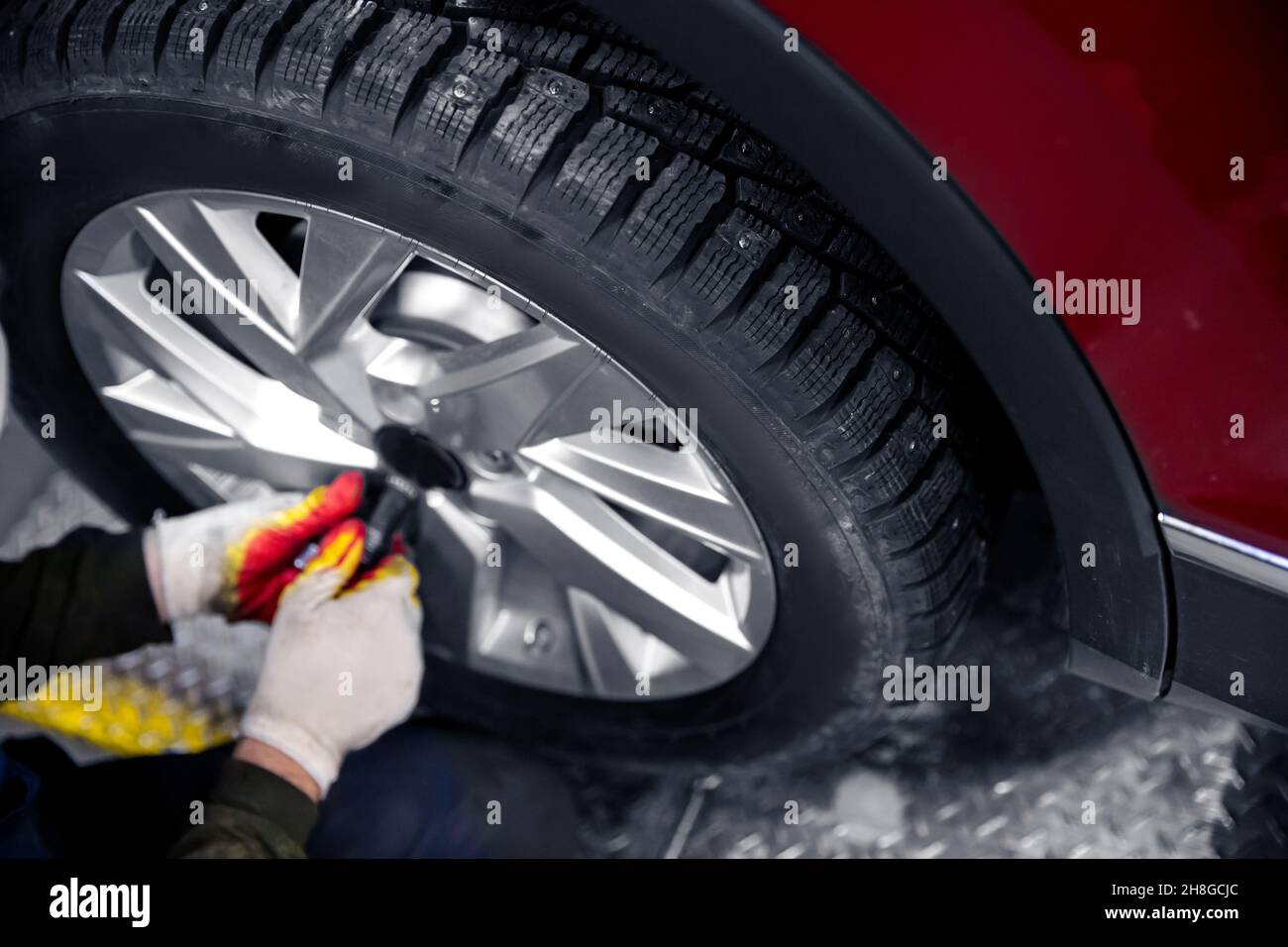Auto mechanic tightens bolts on wheel with automatic key in garage, top ...